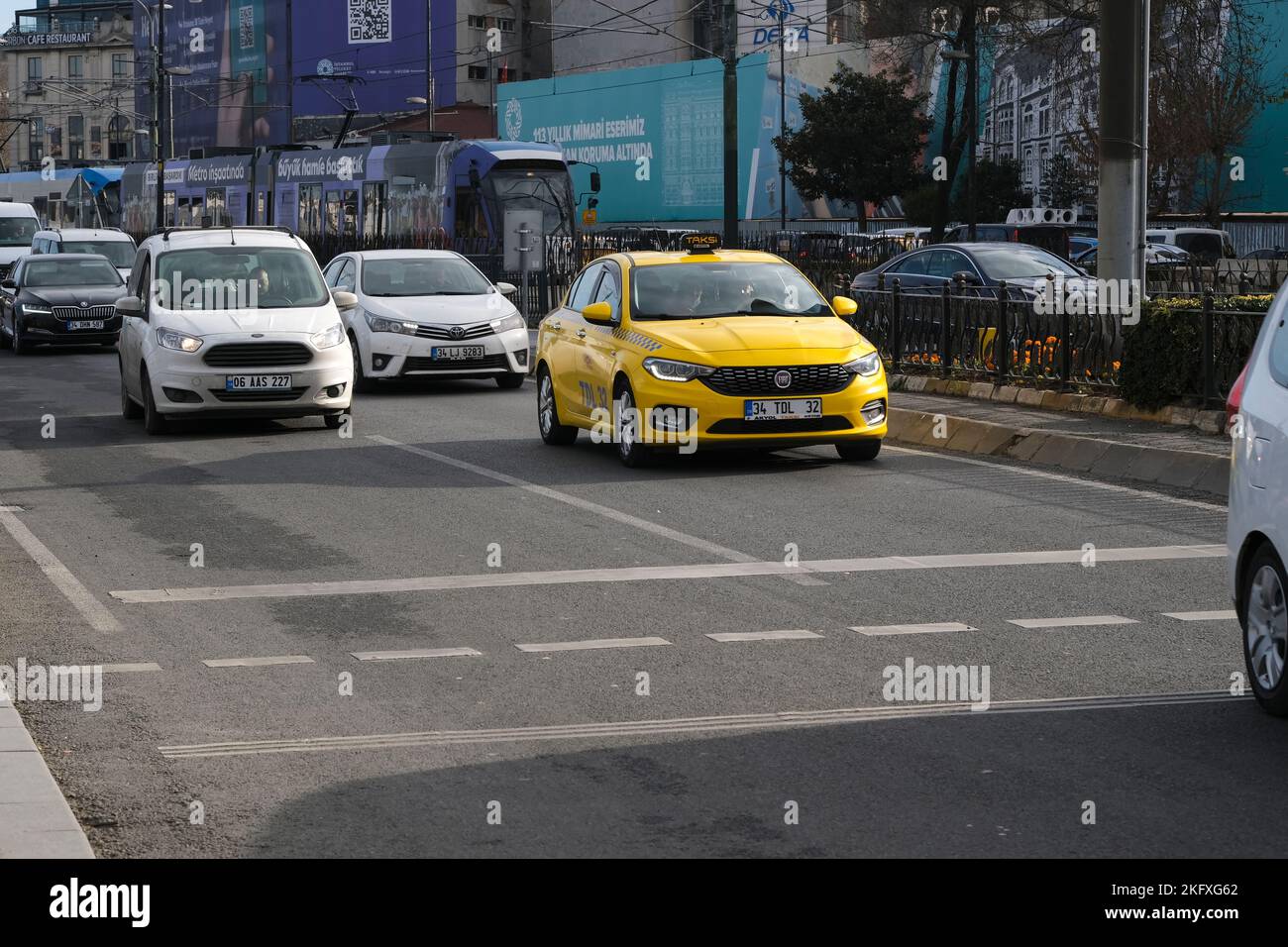 A yellow taxi on the road with other cars in traffic on the street in ...