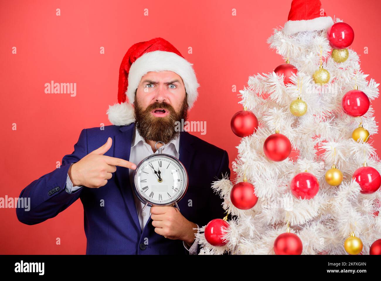 Time to celebrate. Man bearded wear suit and santa hat hold clock ...