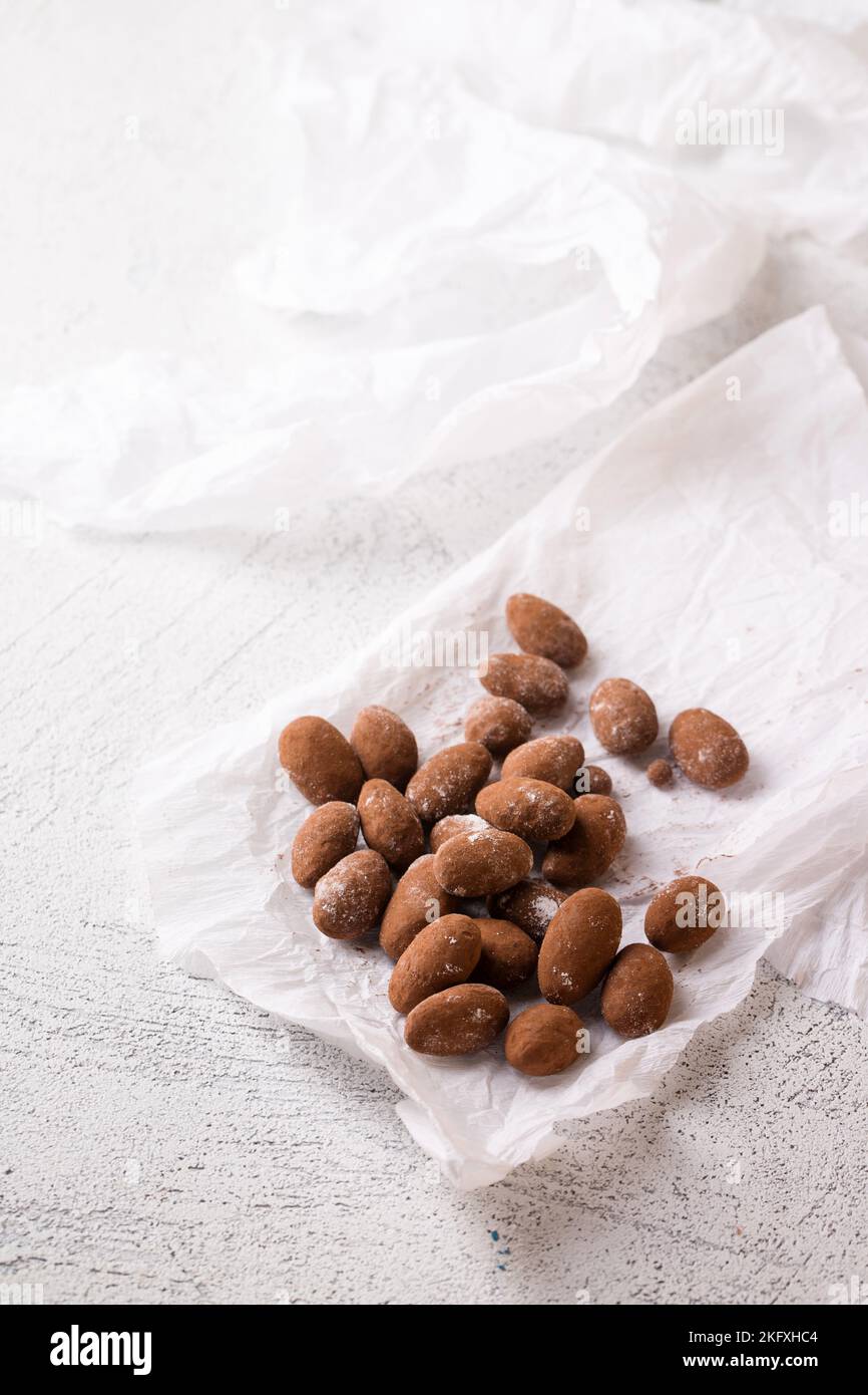Roasted almonds in chocolate and cocoa powder on a white background ...