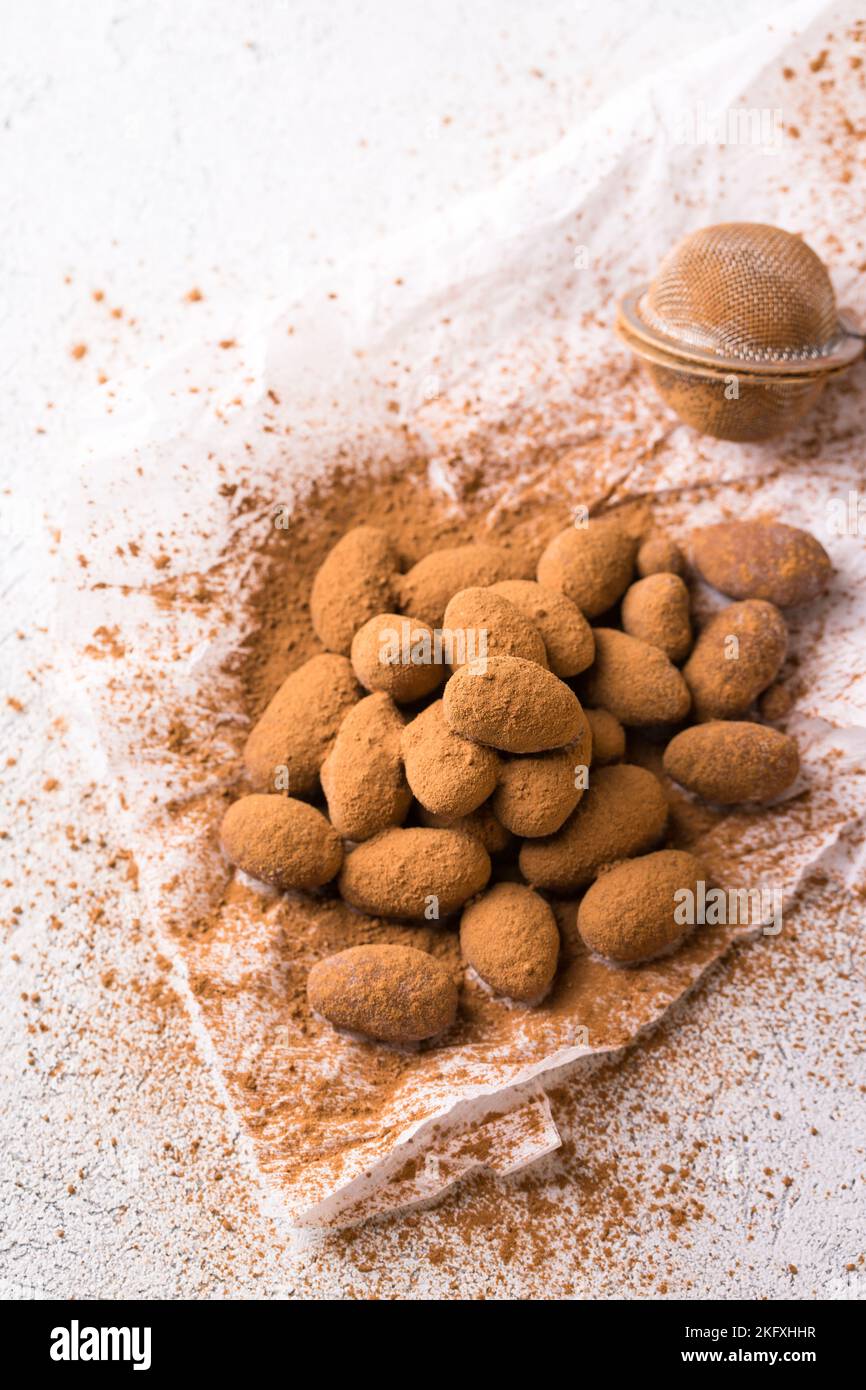 Roasted almonds in chocolate and cocoa powder on a white background ...