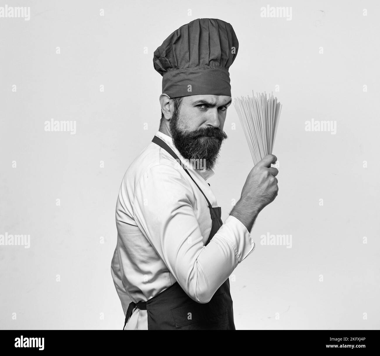 Cook with strict face in burgundy uniform holds dry pasta Stock Photo ...
