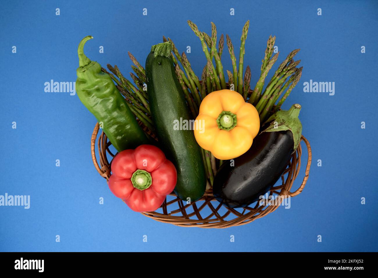 Closeup Overhead Shot Group Of Edible Vegetables Inside A Wicker Basket On A Blue Background