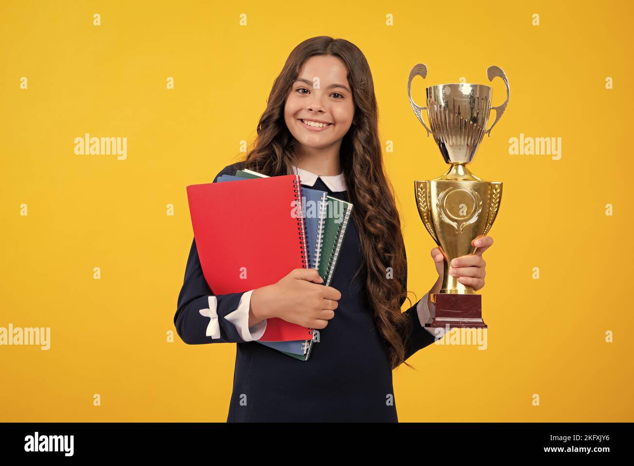 Schoolgirl in school uniform celebrating victory with trophy. Teen ...