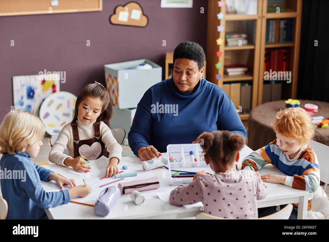 Mature African American teacher sitting among group of intercultural ...