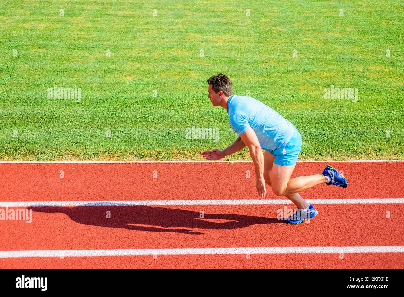Man athlete runner push off starting position stadium path sunny day ...