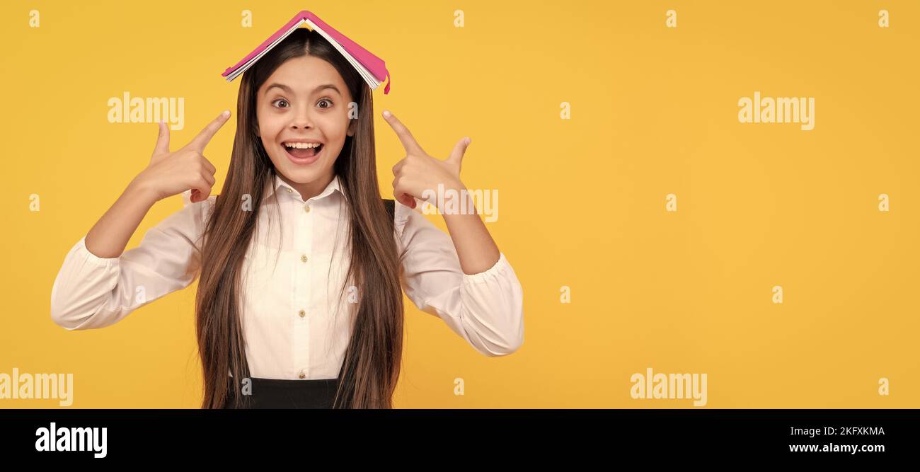 happy teen girl in school uniform pointing finger book on head, learn ...