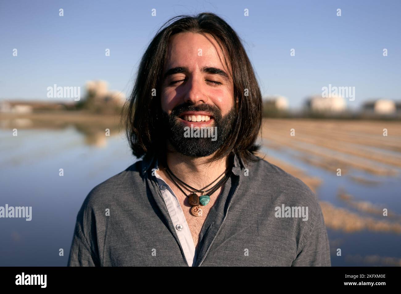 young caucasian man with beard and long hair standing with closed eyes ...