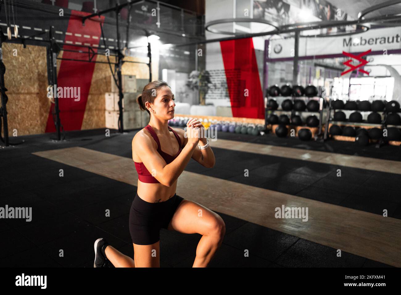 Caucasian brunette girl on her knees doing sports alone in a large gym ...