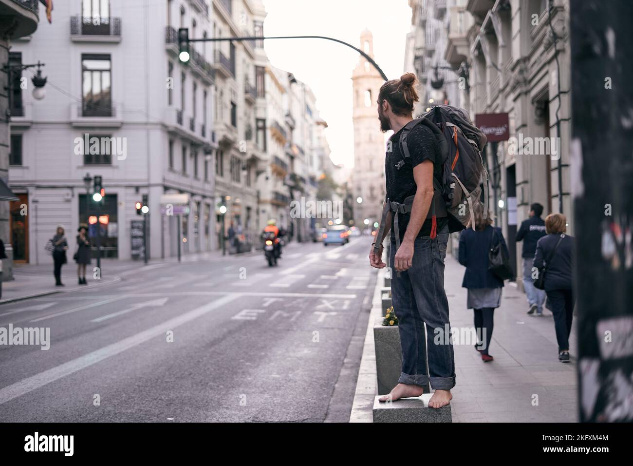 caucasian guy with beard long hair t-shirt and blue pants barefoot in ...