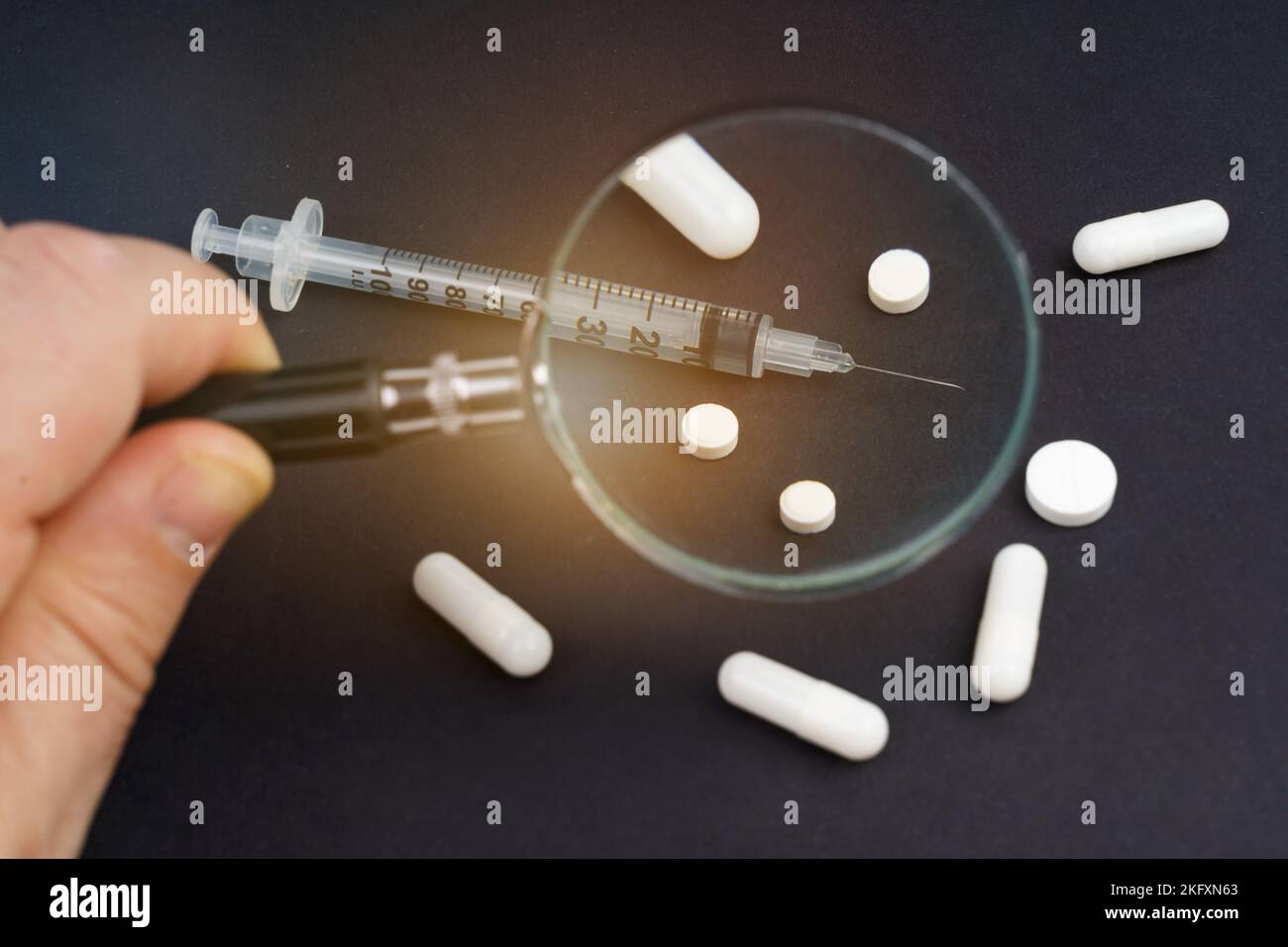Medicine and health concept. A syringe and pills lie on a black ...