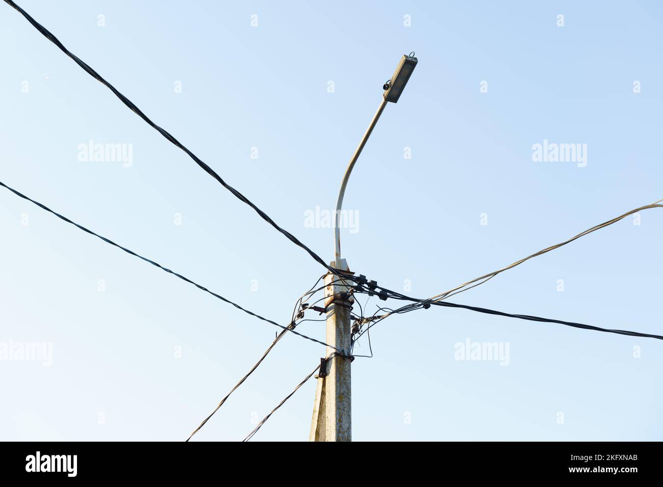 Street lamp and electric wires leading to it against the background of ...
