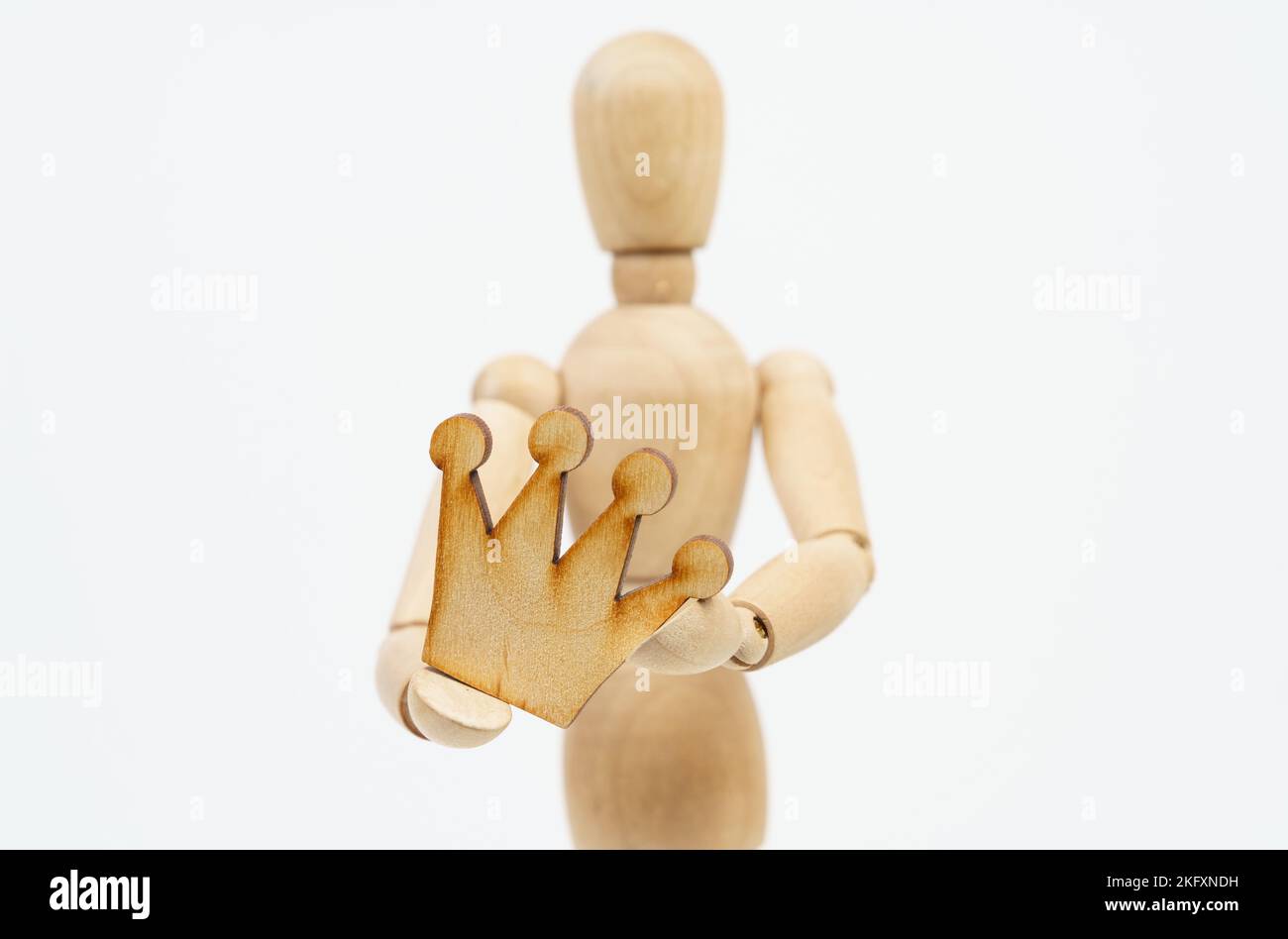 Business and leader concept. The wooden man holds a crown in his hands ...