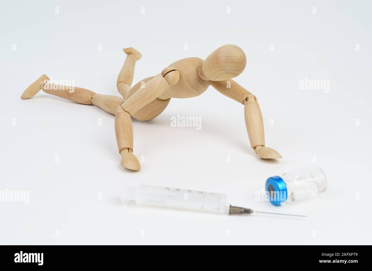 Medicine and drugs concept. The wooden man crawls towards the syringe ...