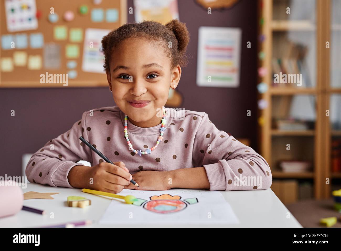 Cute successful learner of primary school looking at camera with smile ...