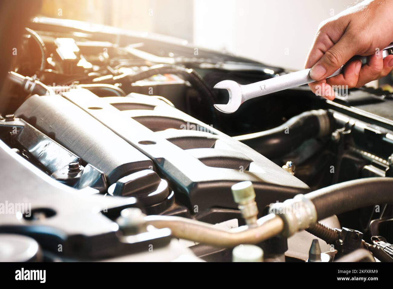 Auto mechanic hand holding open-end spanner on the engine compartment ...