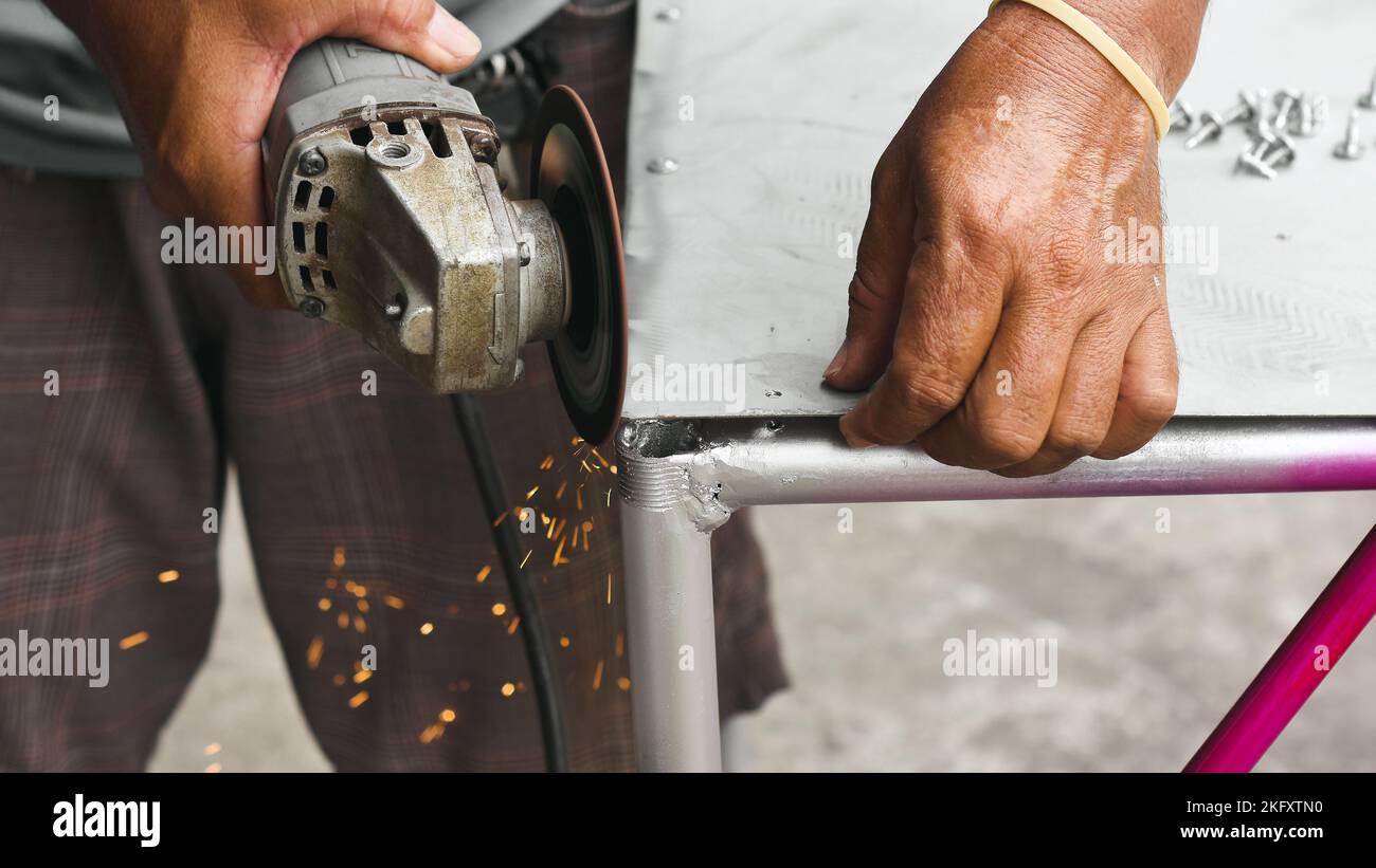 A mechanic is cutting sheet metal using an electric wheel grinding in ...