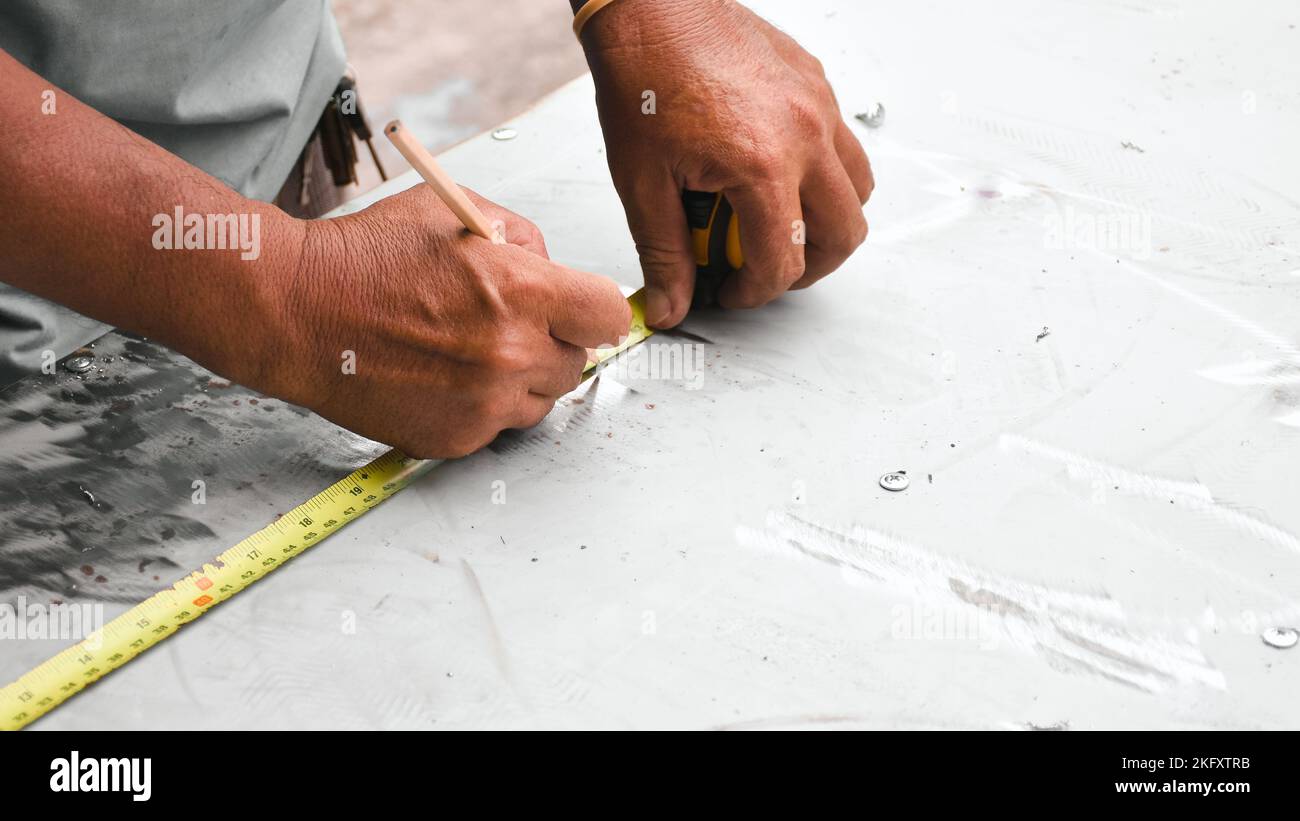 The technician measures the length of the metal plate with a measuring ...
