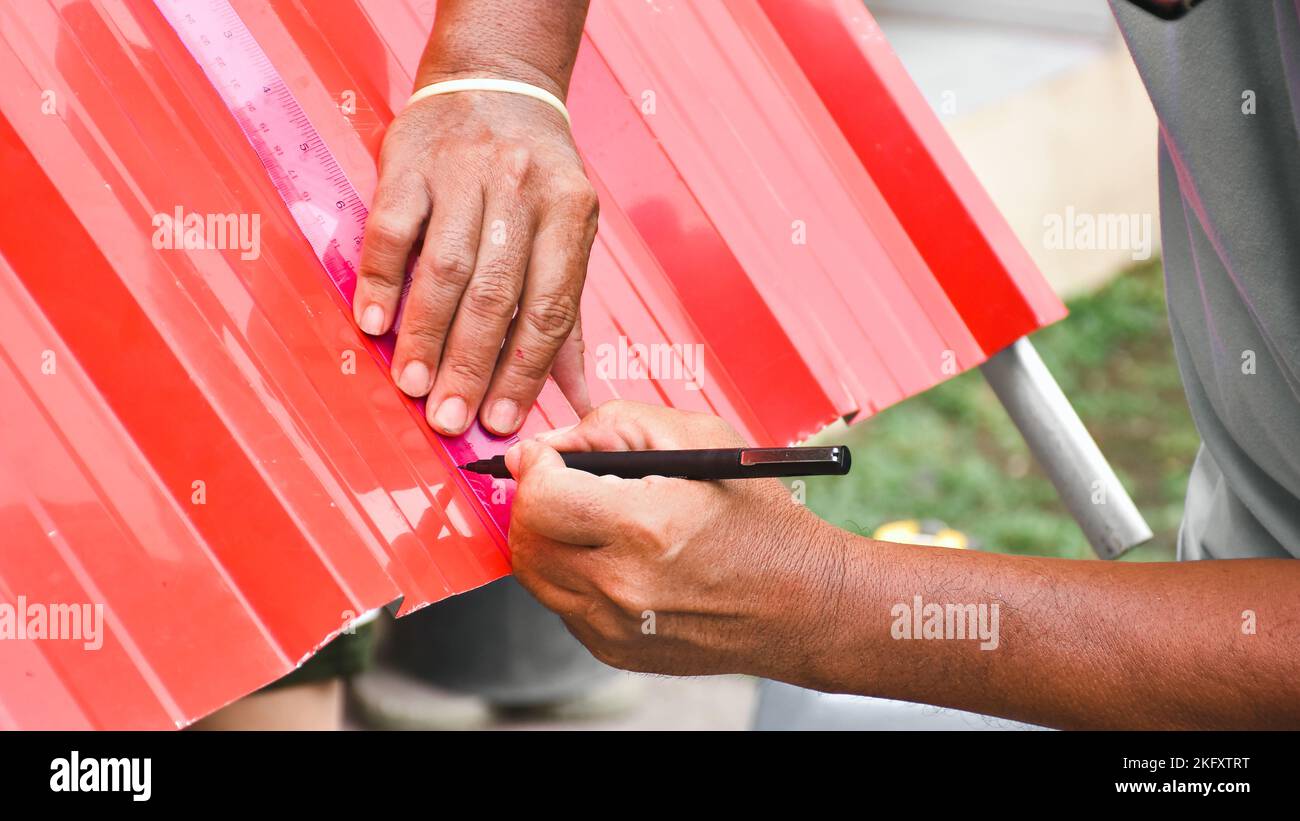 The technician measures the length of the metal sheet with a measuring ...
