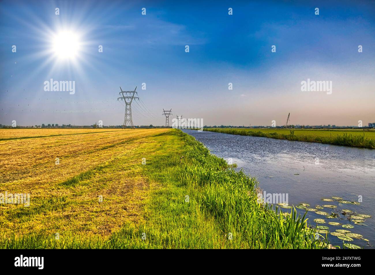 Dutch landscape with a canal and grass fields with mirror reflection in ...