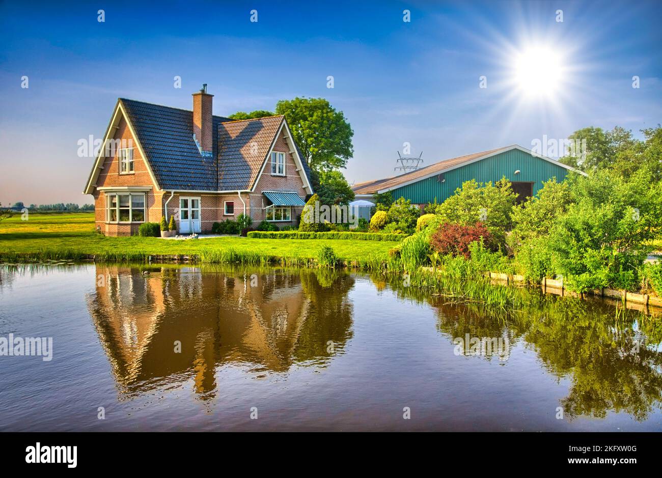 Red bricks house in countryside near the lake with mirror reflection in ...