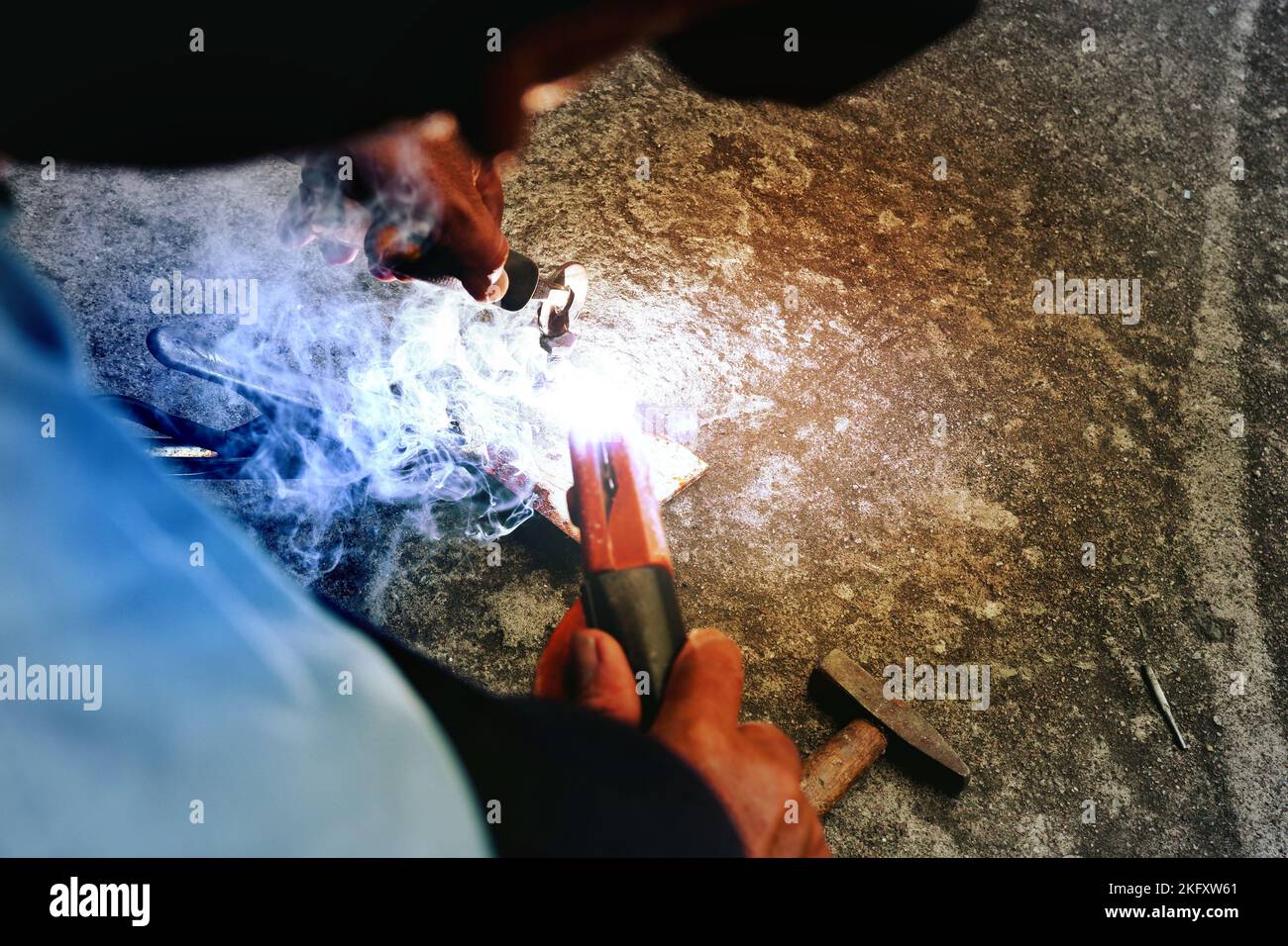 A technician is welding sheet metal with a welding machine in a factory ...