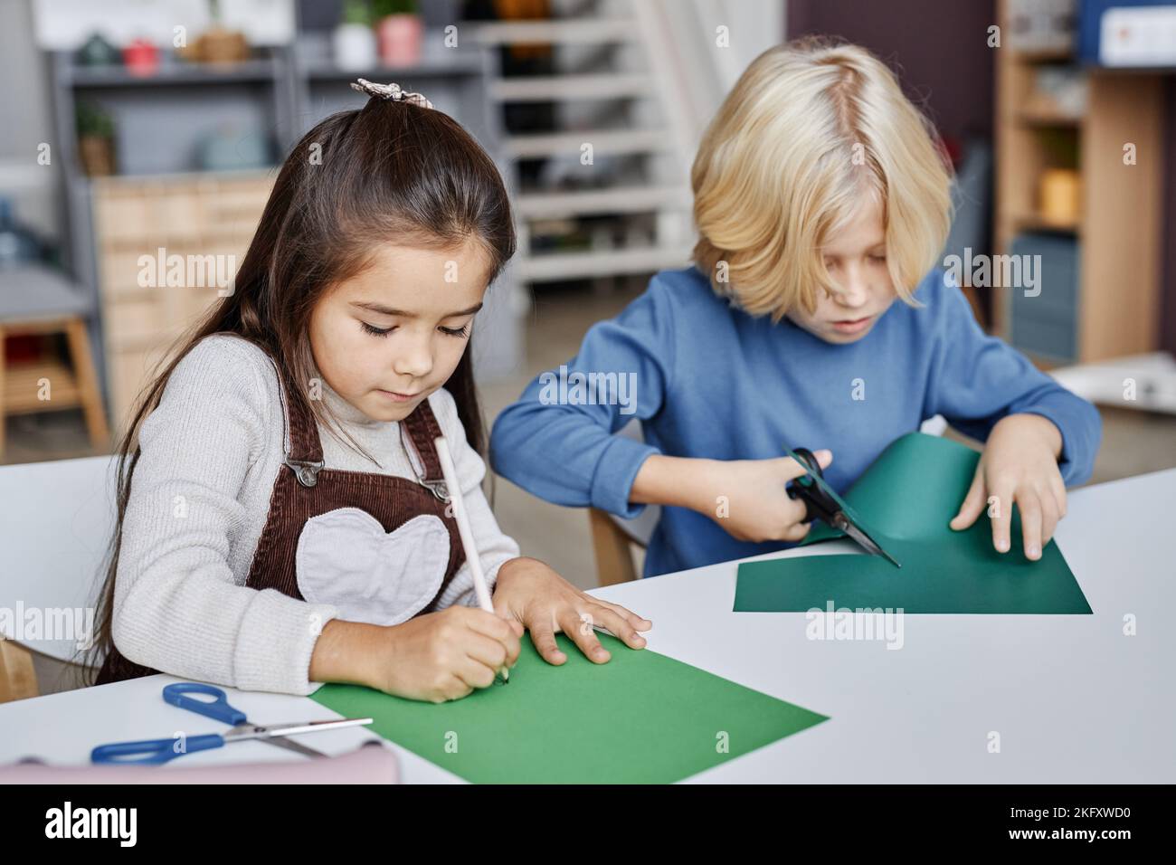 Diligent learner of primary school drawing on dark green paper while ...