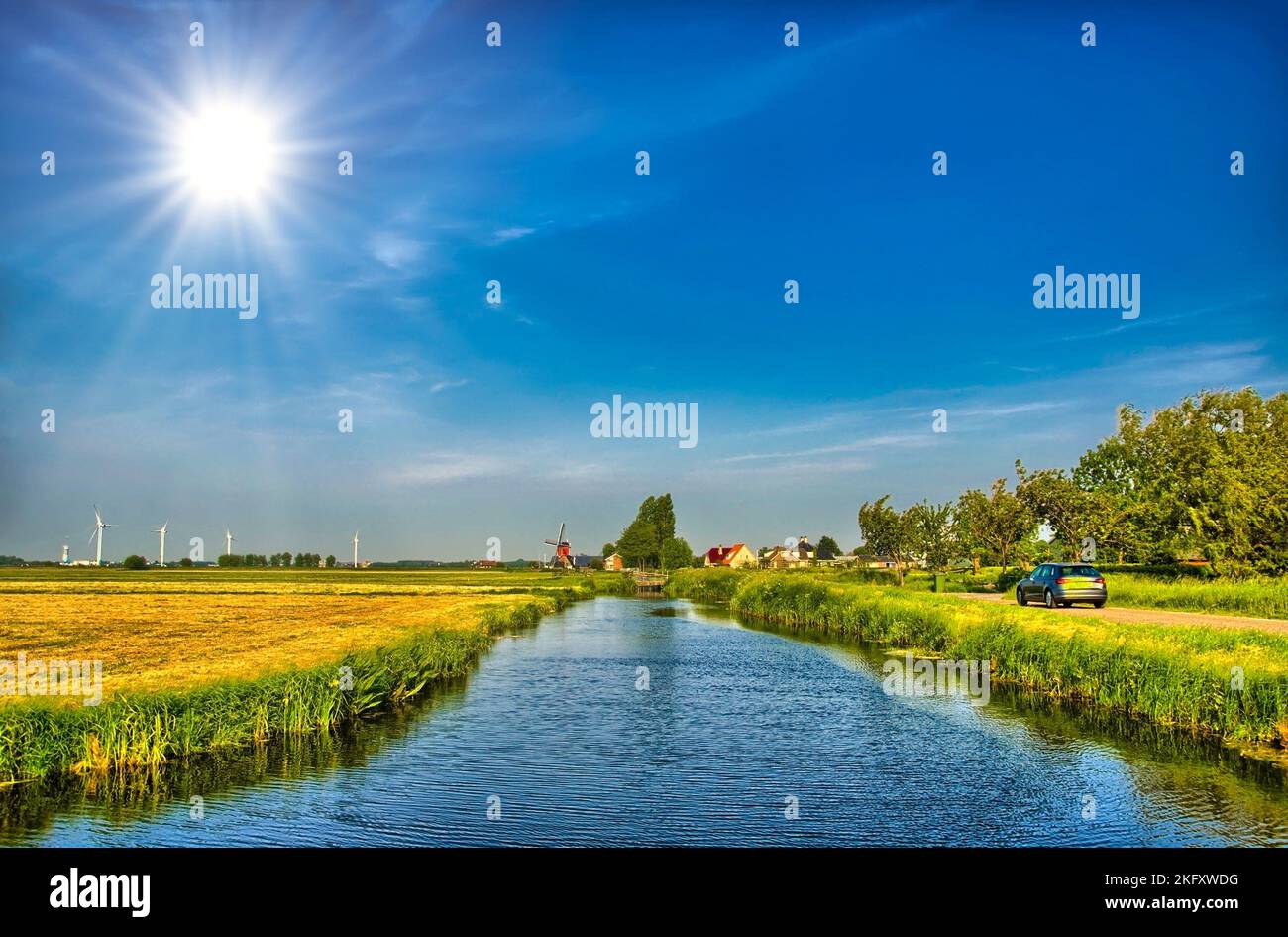 Dutch landscape with a canal and grass fields with mirror reflection in ...