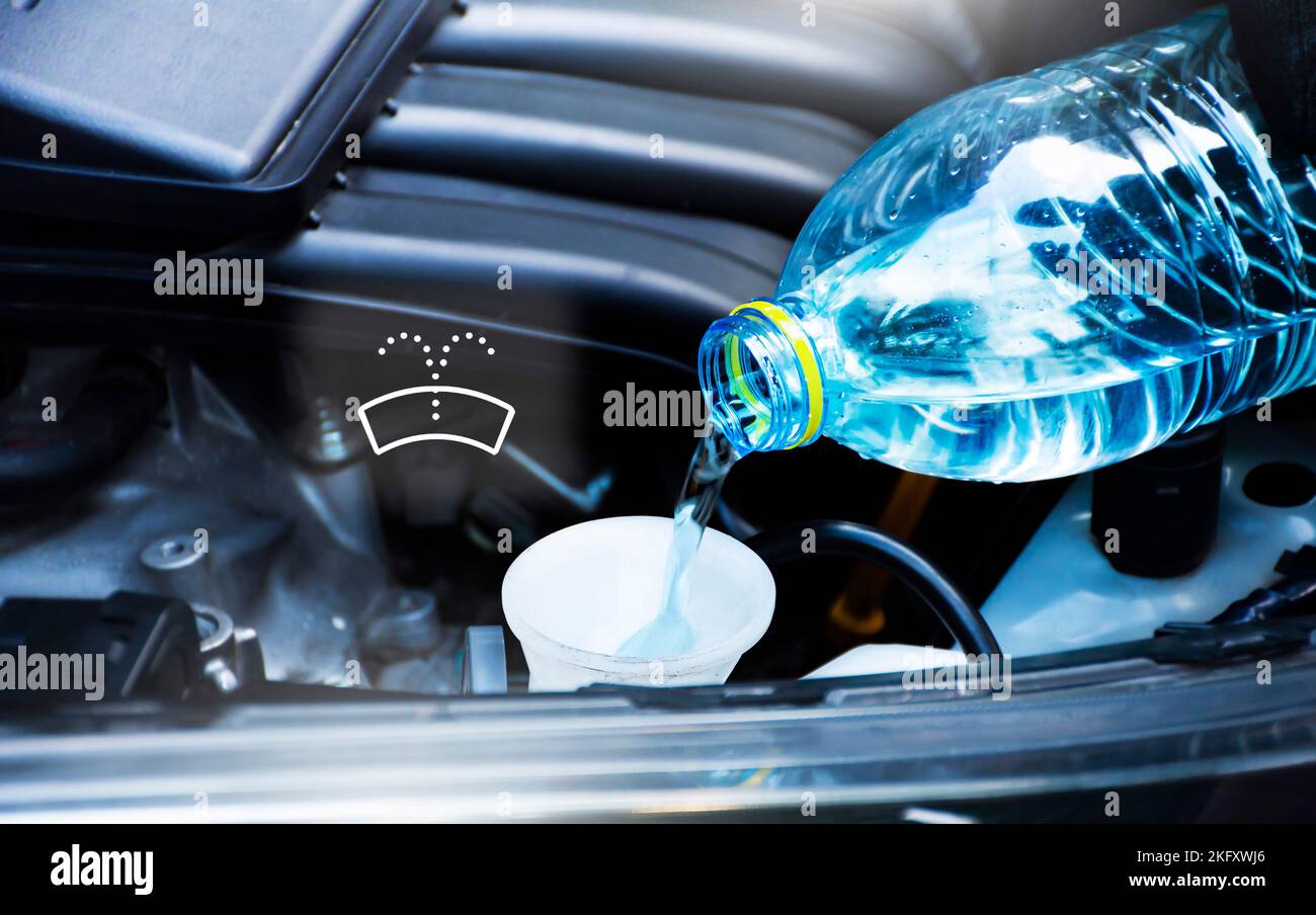 Mechanic hand is filling clean water into windshield washer water tank ...