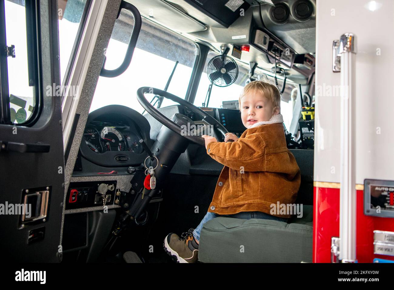 A child holds the steering wheel of a fire truck during an open house ...
