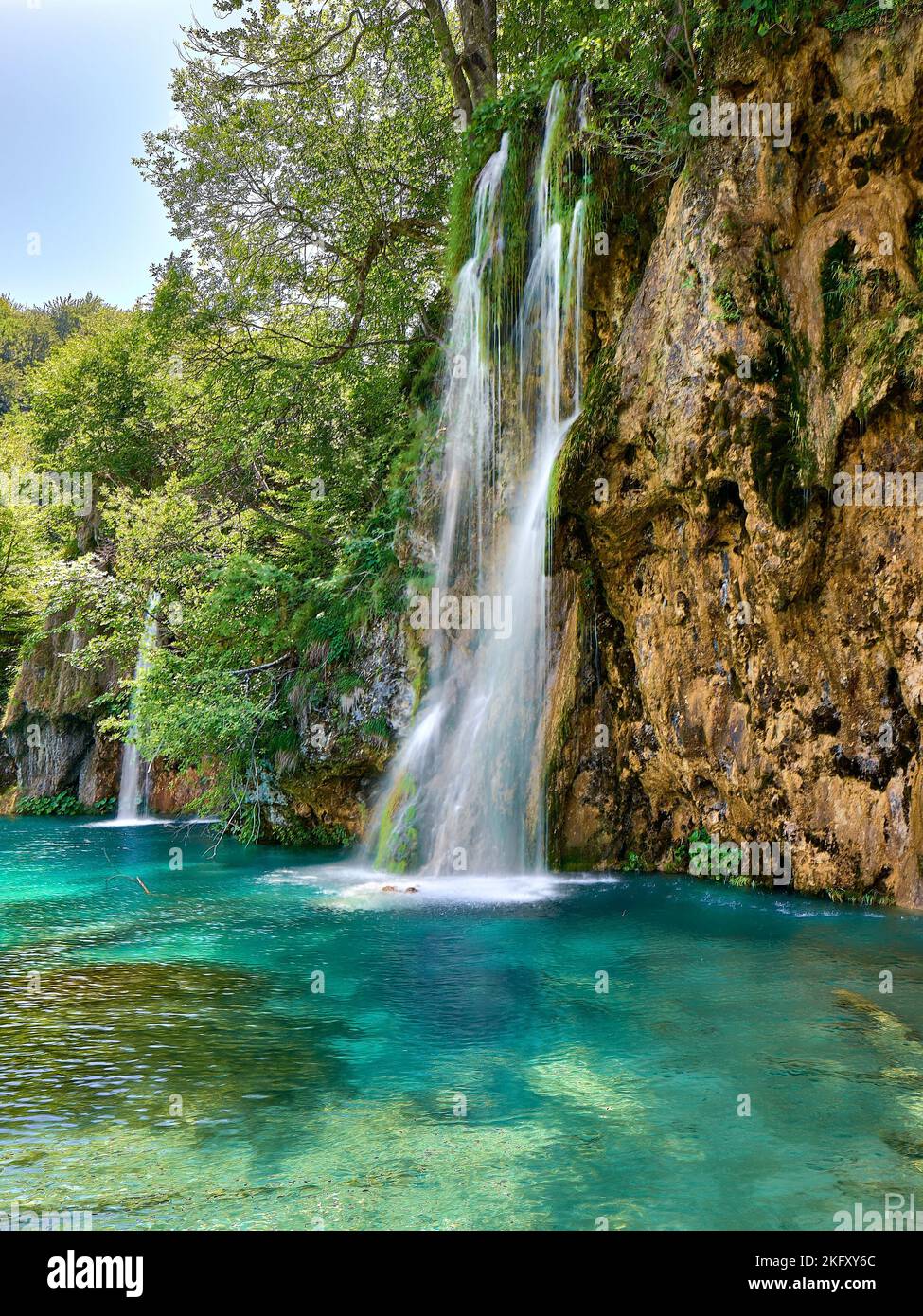 A vertical shot of a waterfall coming out from a cliff Stock Photo - Alamy