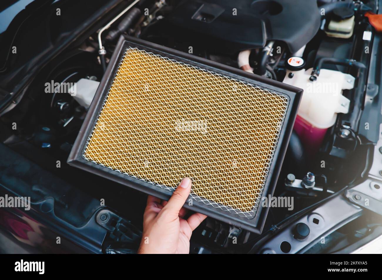 A auto mechanic carries a replacement car air filter for car engine ...