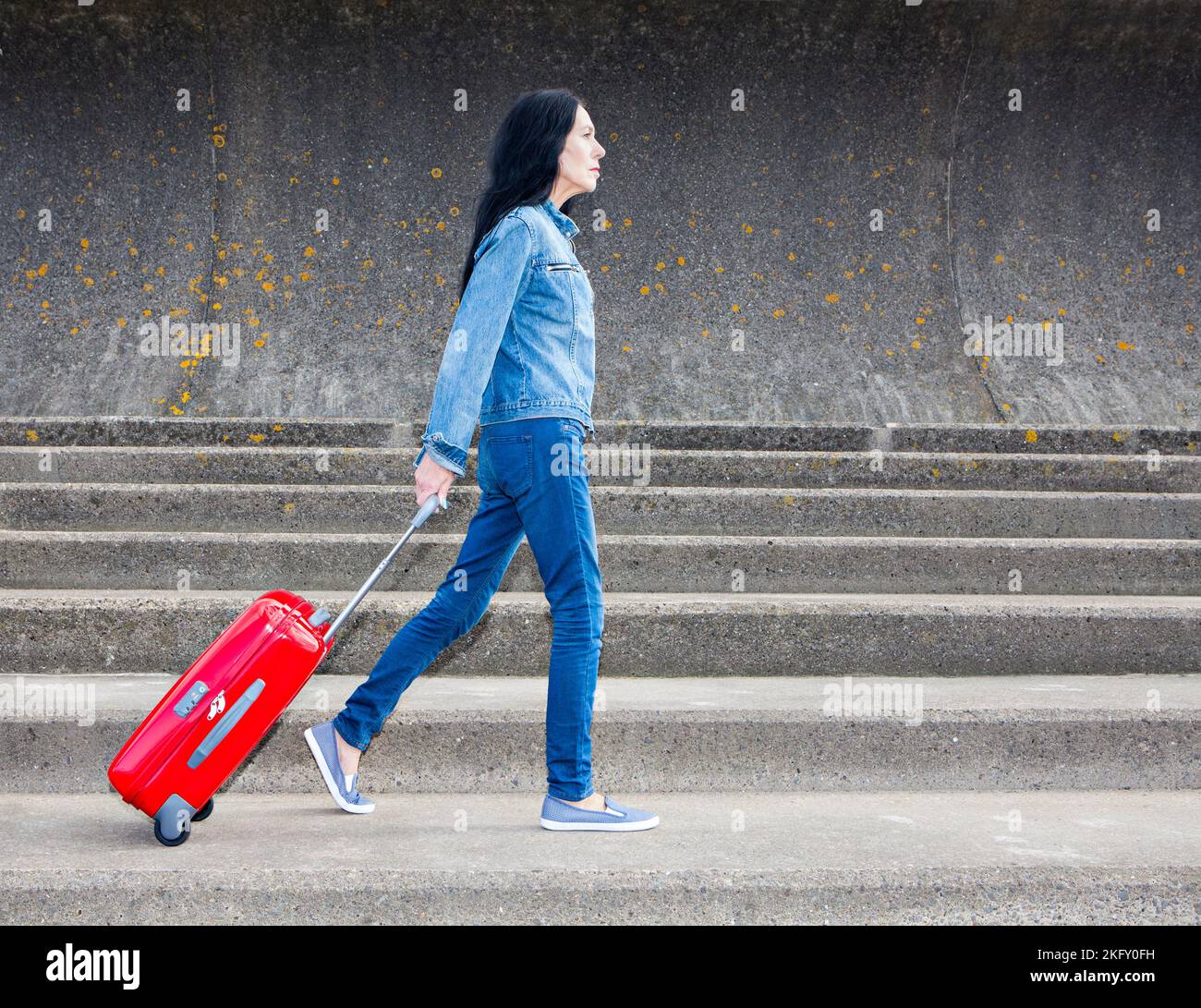 Woman walking with red luggage, side view Stock Photo - Alamy