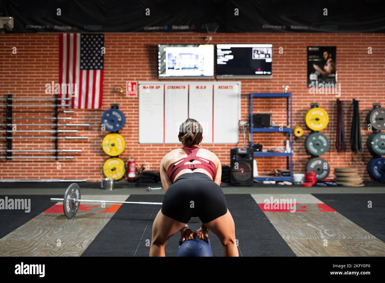 Caucasian young woman on her back crouching about to lift a large heavy ...