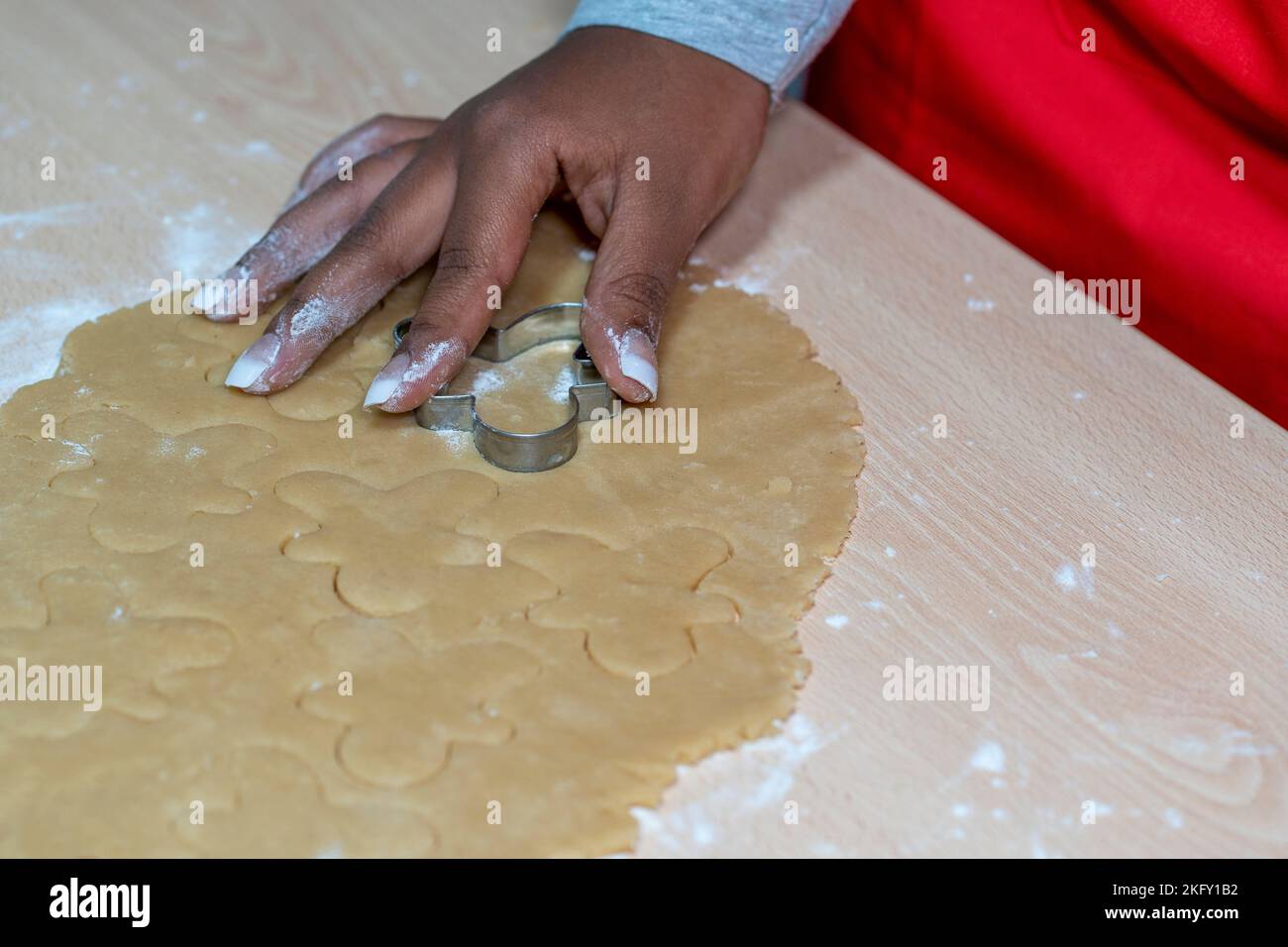 young African-American girl cutting biscuit dough in the shape of a ...
