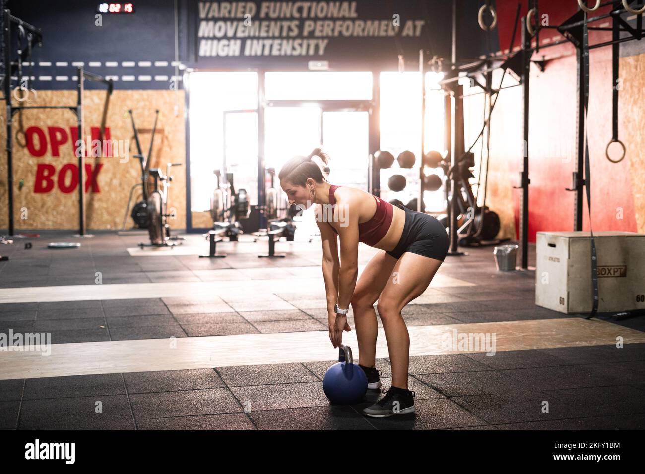 caucasian girl doing sports in a large gym about to lift a large heavy ...