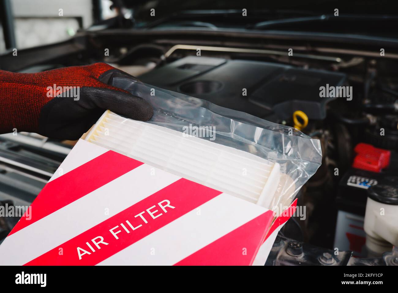 A brand-new air filter in its box is being held holds by an auto ...