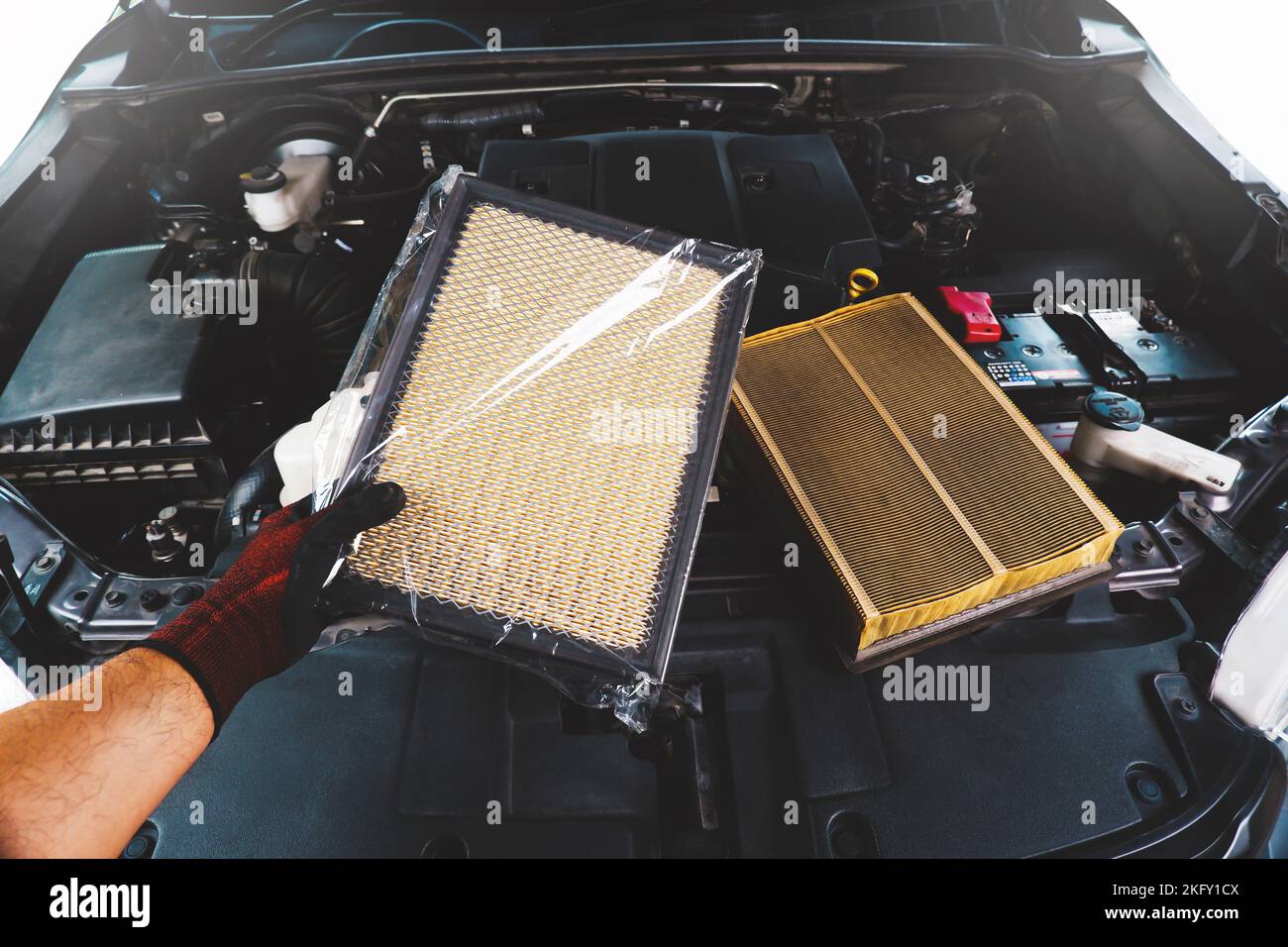 A auto mechanic holds a brand new air filter that is wrapped in plastic ...