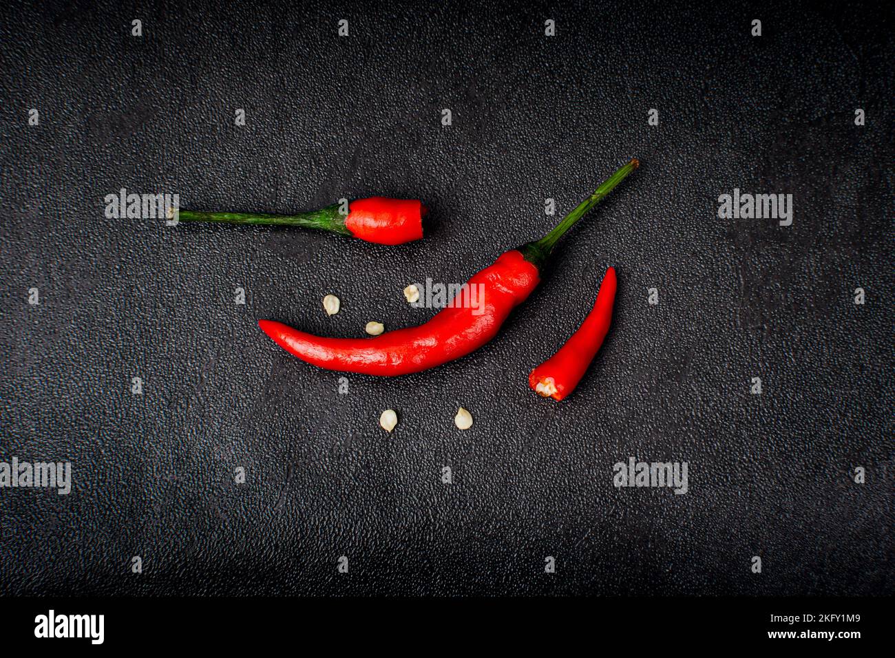 Red hot chilli peppers and half broken chilli on a black background ...