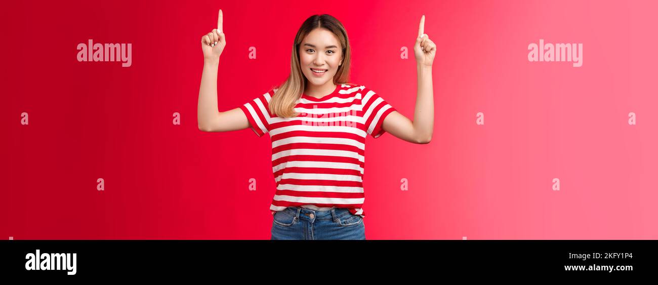 Hey up we go. Cheerful good-looking young asian girl pointing hands up ...