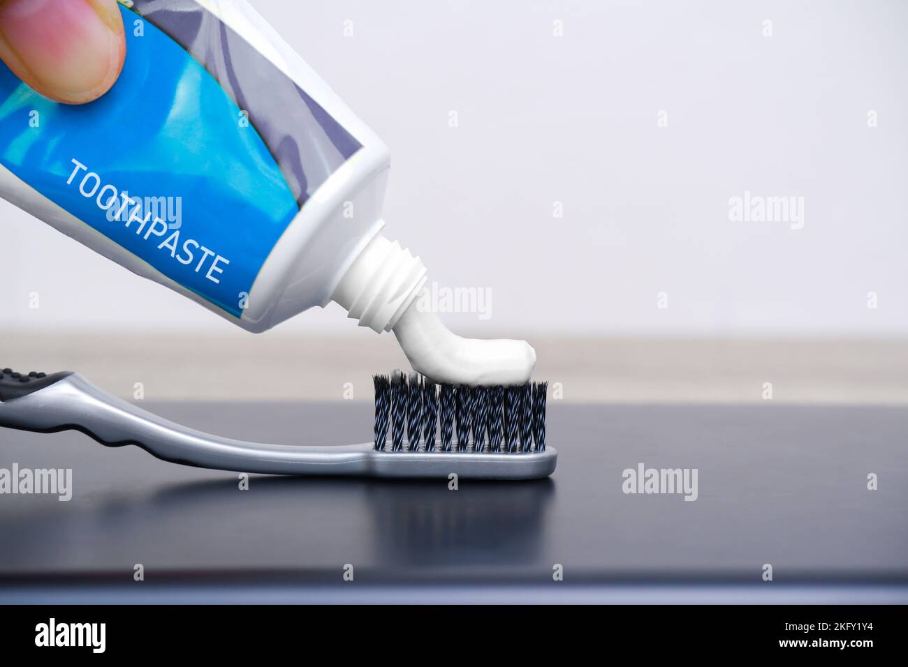 Hand squeezed white toothpaste onto a gray toothbrush with a right copy ...