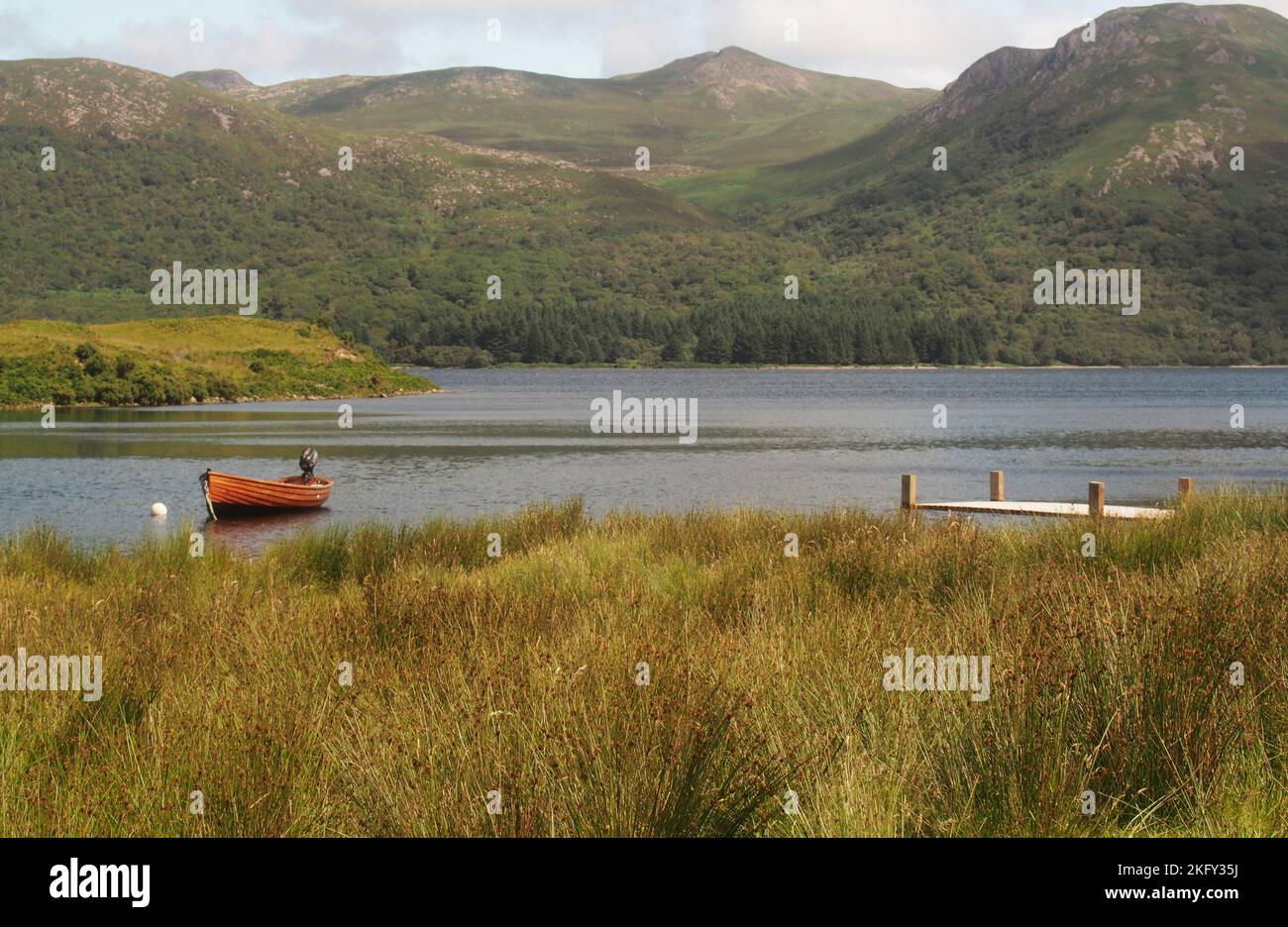 A small jetty and boat with outboard motor on Loch Ba, Mull, Scotland ...