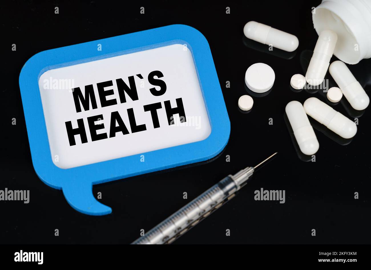 Medical concept. On a black surface, a syringe, pills and a blue frame ...