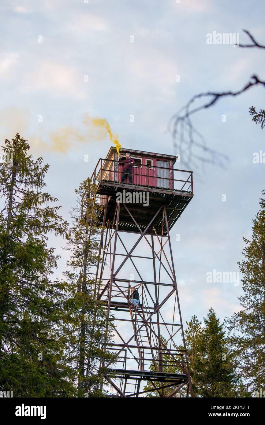A vertical low angle of a man standing on a forest fire lookout tower ...