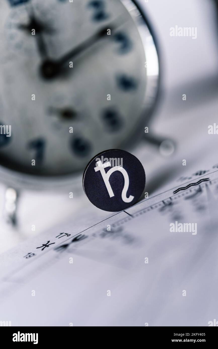 A zodiacal symbol Saturn on a drawing of a natal chart and a defocused ...