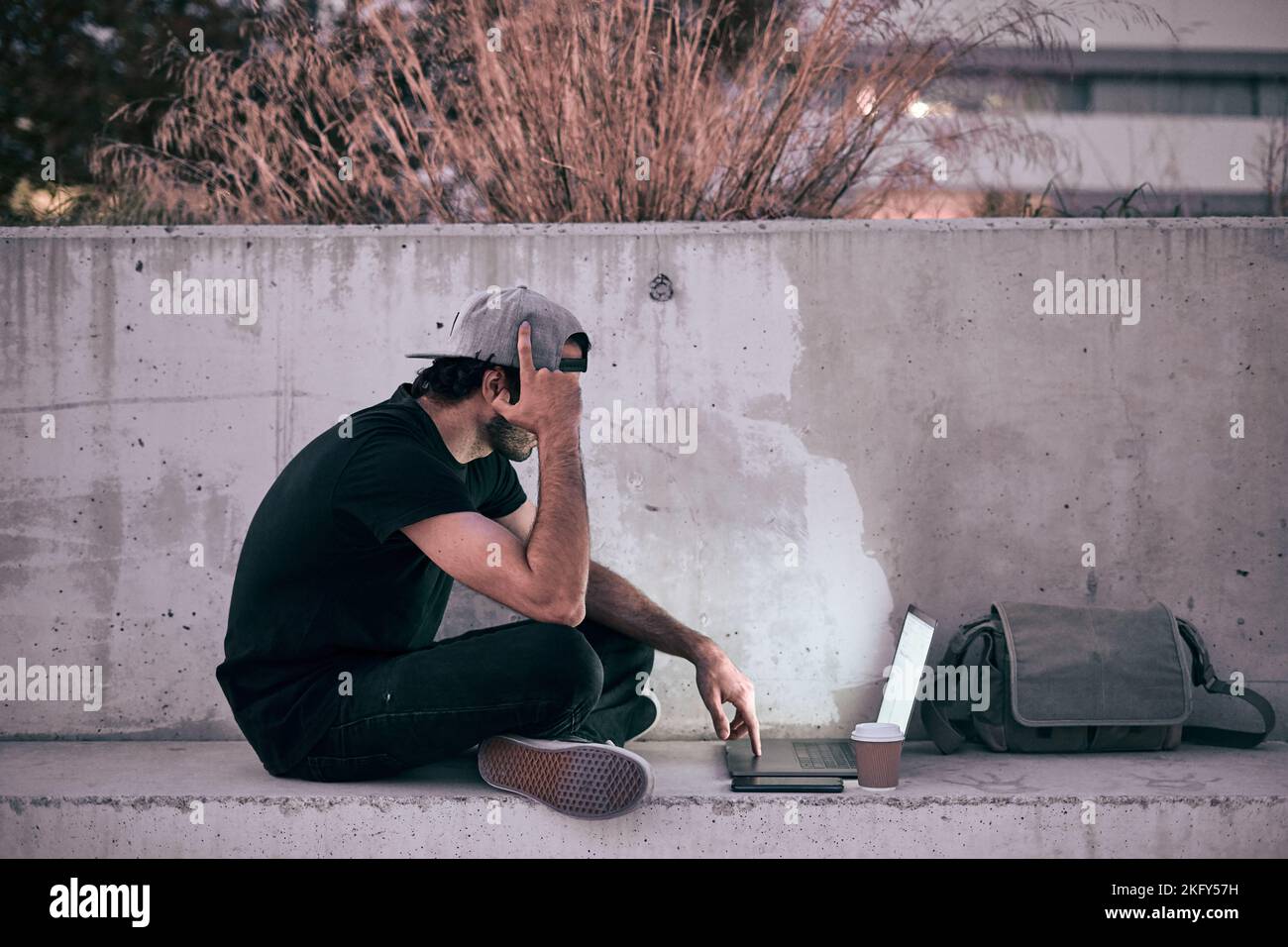 caucasian guy in gray cap black t-shirt sitting on the concrete floor ...