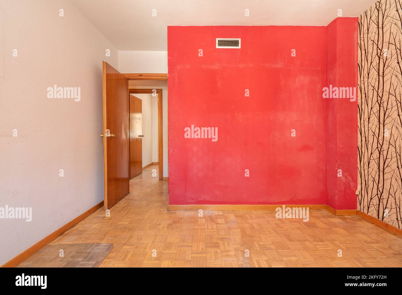 Empty room with poorly painted red walls, oak parquet floors and wooden ...