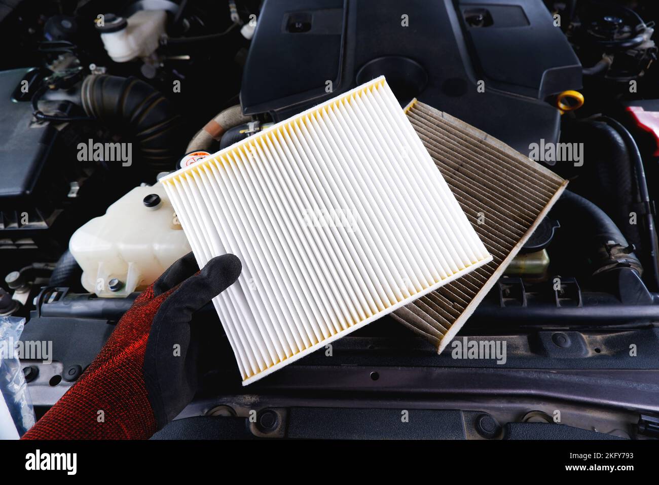 New air filter in a hand and old filthy filter placed on the car engine ...