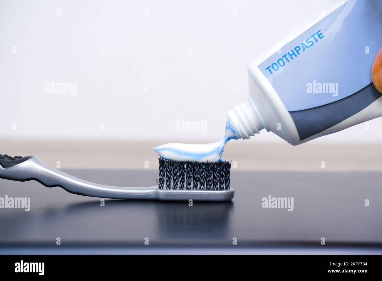 Hand squeezed white toothpaste onto a gray toothbrush with a left copy ...