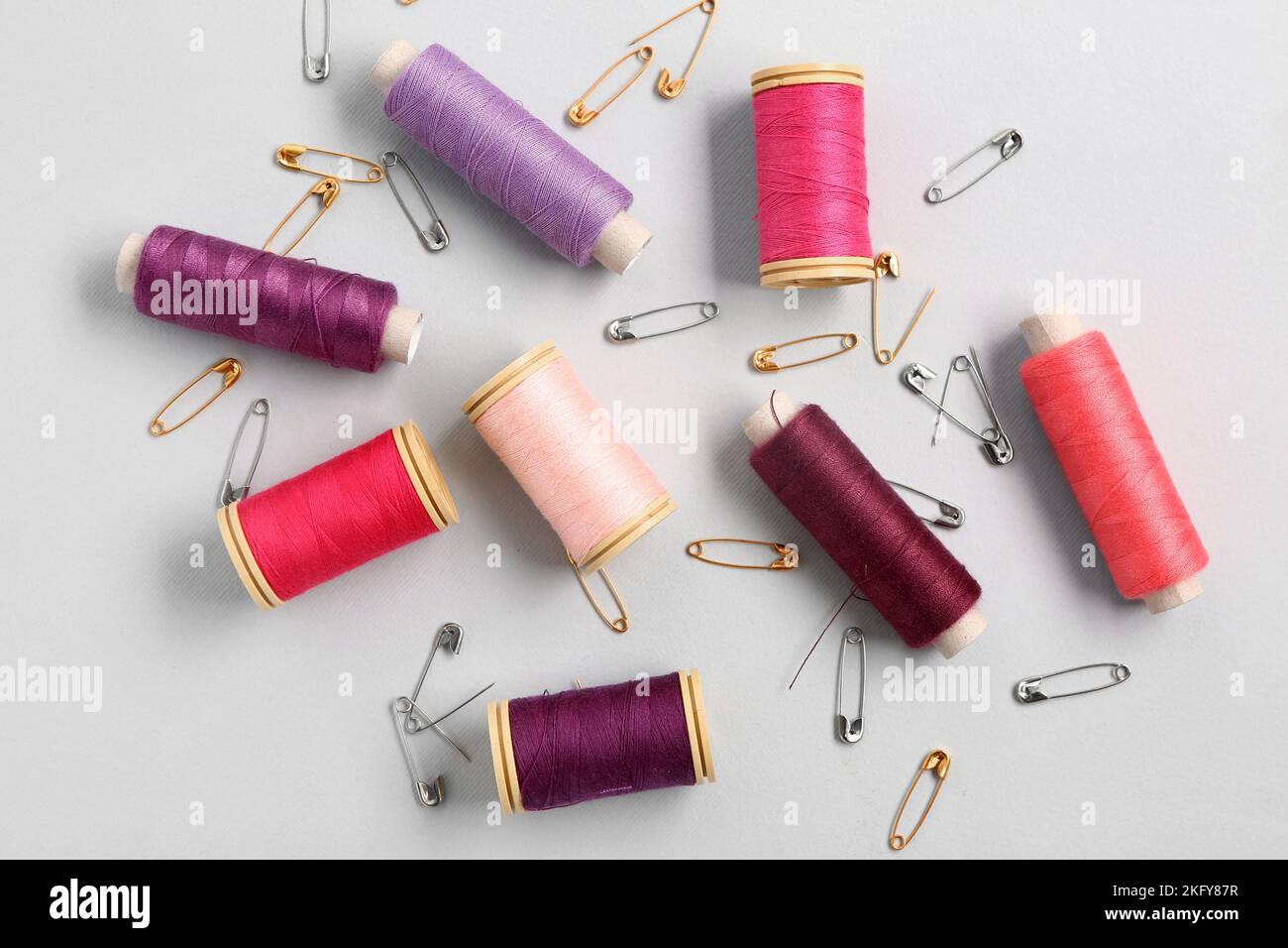 Set of colorful thread spools and safety pins on light background Stock ...