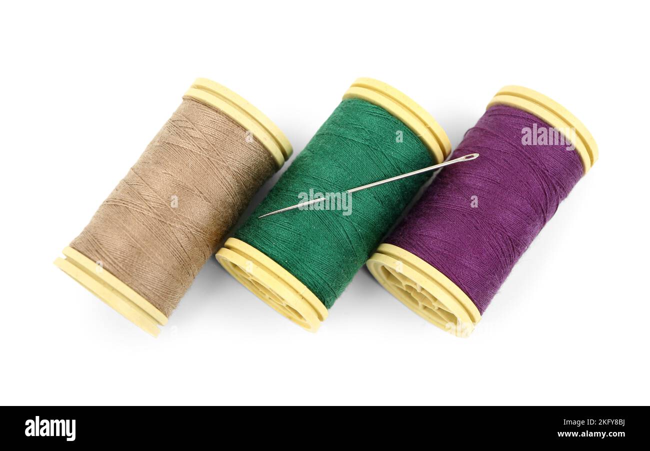 Sewing thread spools with needle on white background Stock Photo - Alamy